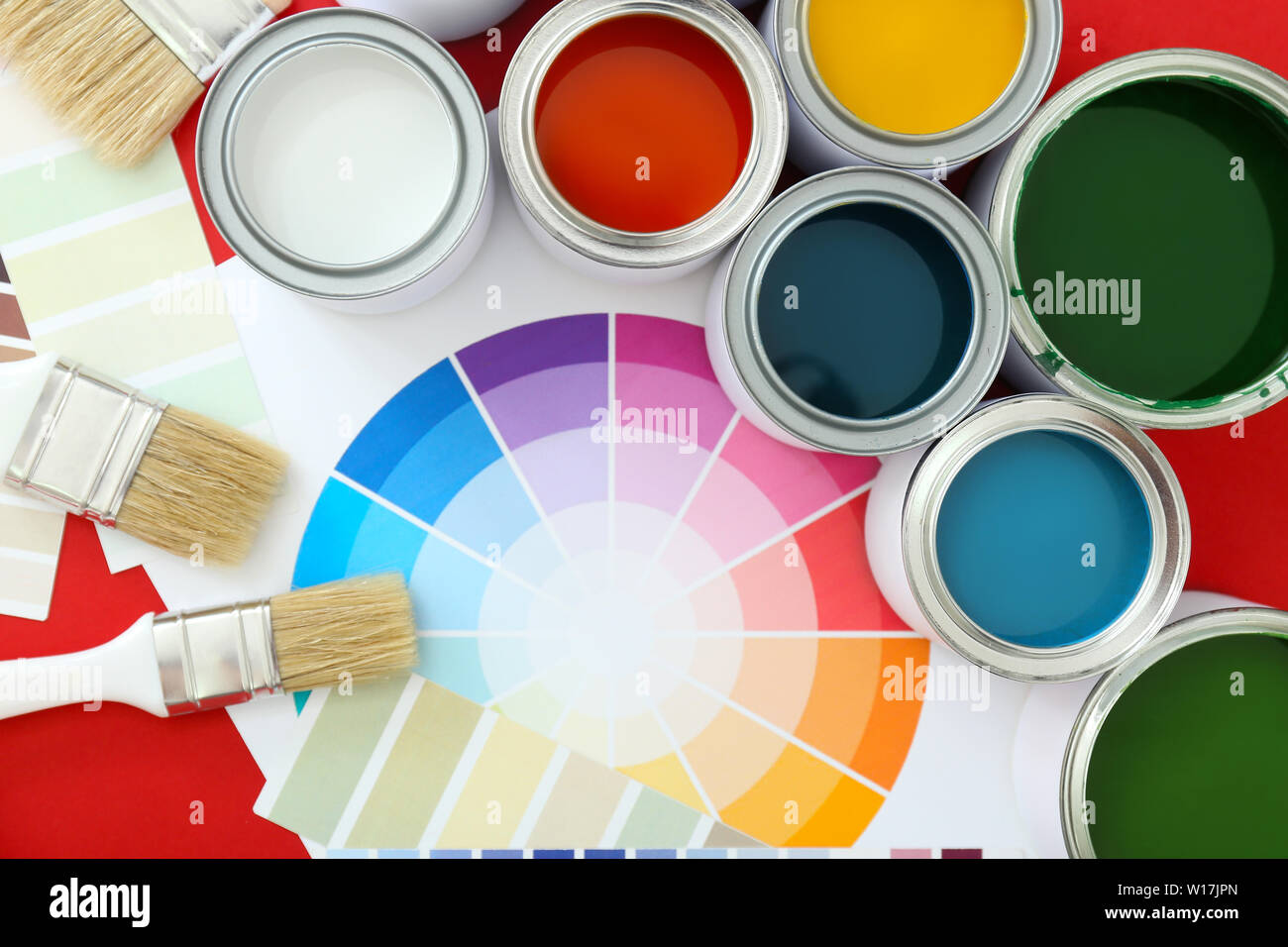 Cans of paints with brushes and palette samples on color background ...