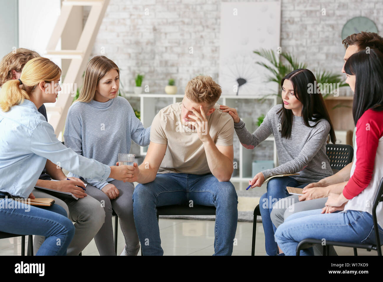 People calming depressed man at group therapy session Stock Photo - Alamy