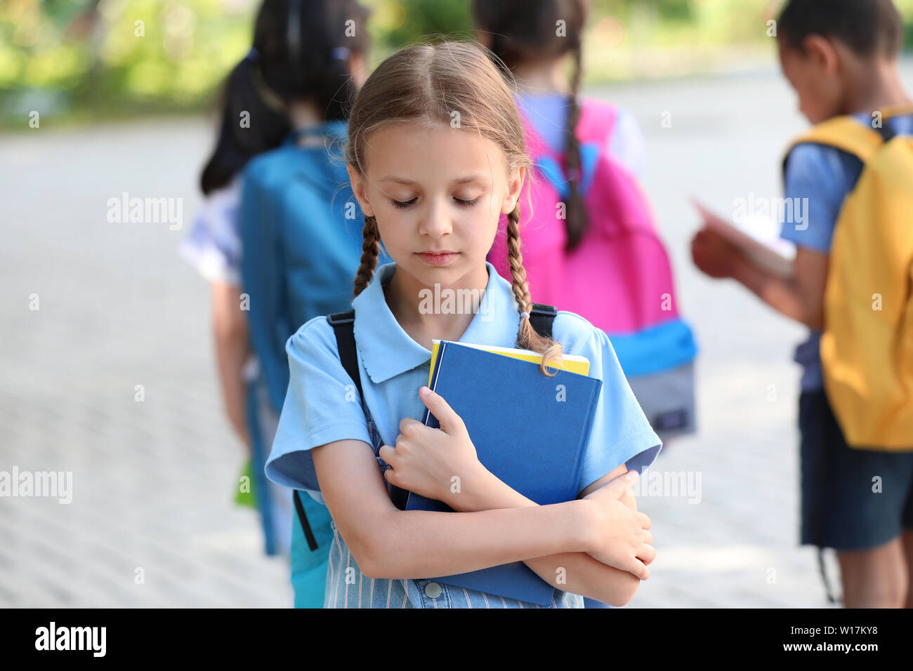 Sad little girl and her classmates outdoors Stock Photo - Alamy