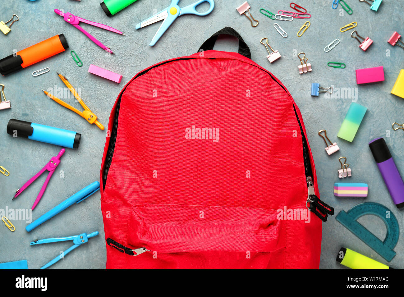 Backpack with school supplies on grey background Stock Photo - Alamy
