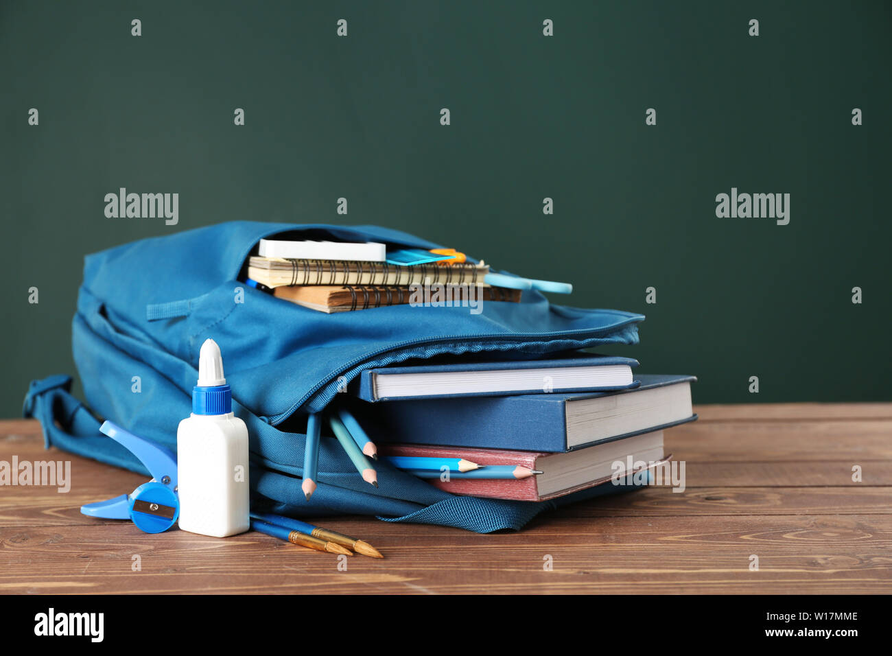 School backpack with stationery on table in classroom Stock Photo - Alamy