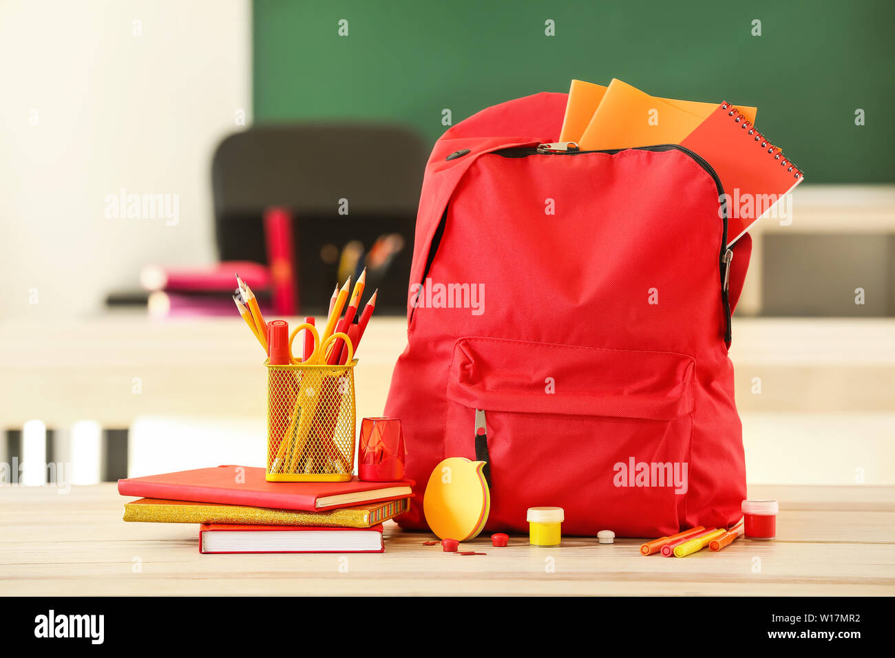 School backpack with stationery on table in classroom Stock Photo - Alamy