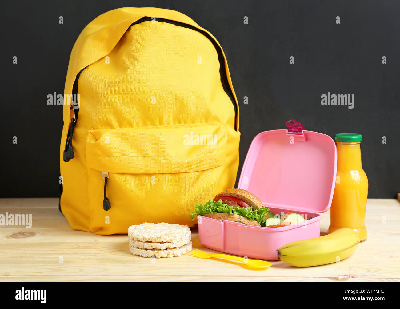 School lunch box with tasty food and backpack on table in classroom ...