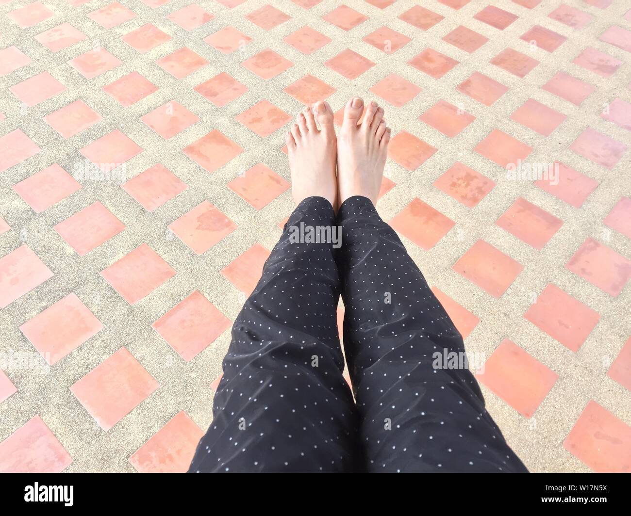 Feet on orange tile floor. Young woman barefoot or feet standing on the ...