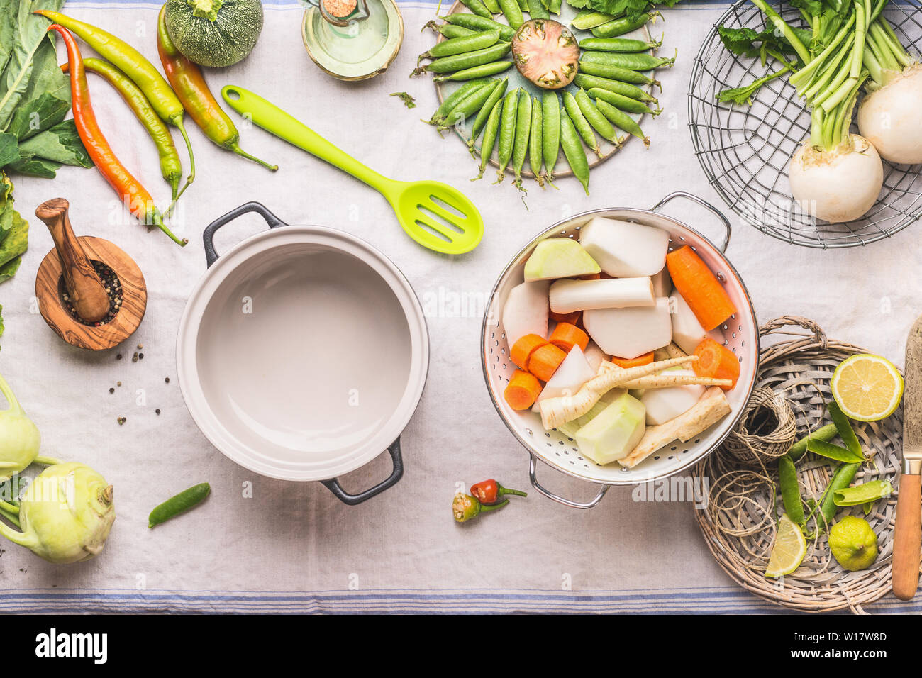 Cooking pot with spoon and white colander with fresh vegetables for ...