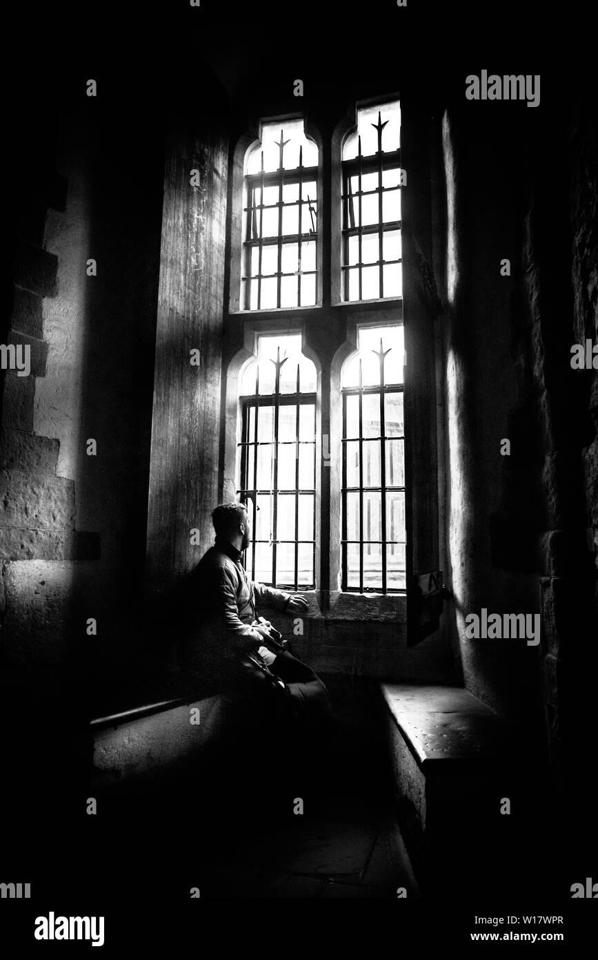 Rear view at silhouette of man sitting in the darkness looking through ...