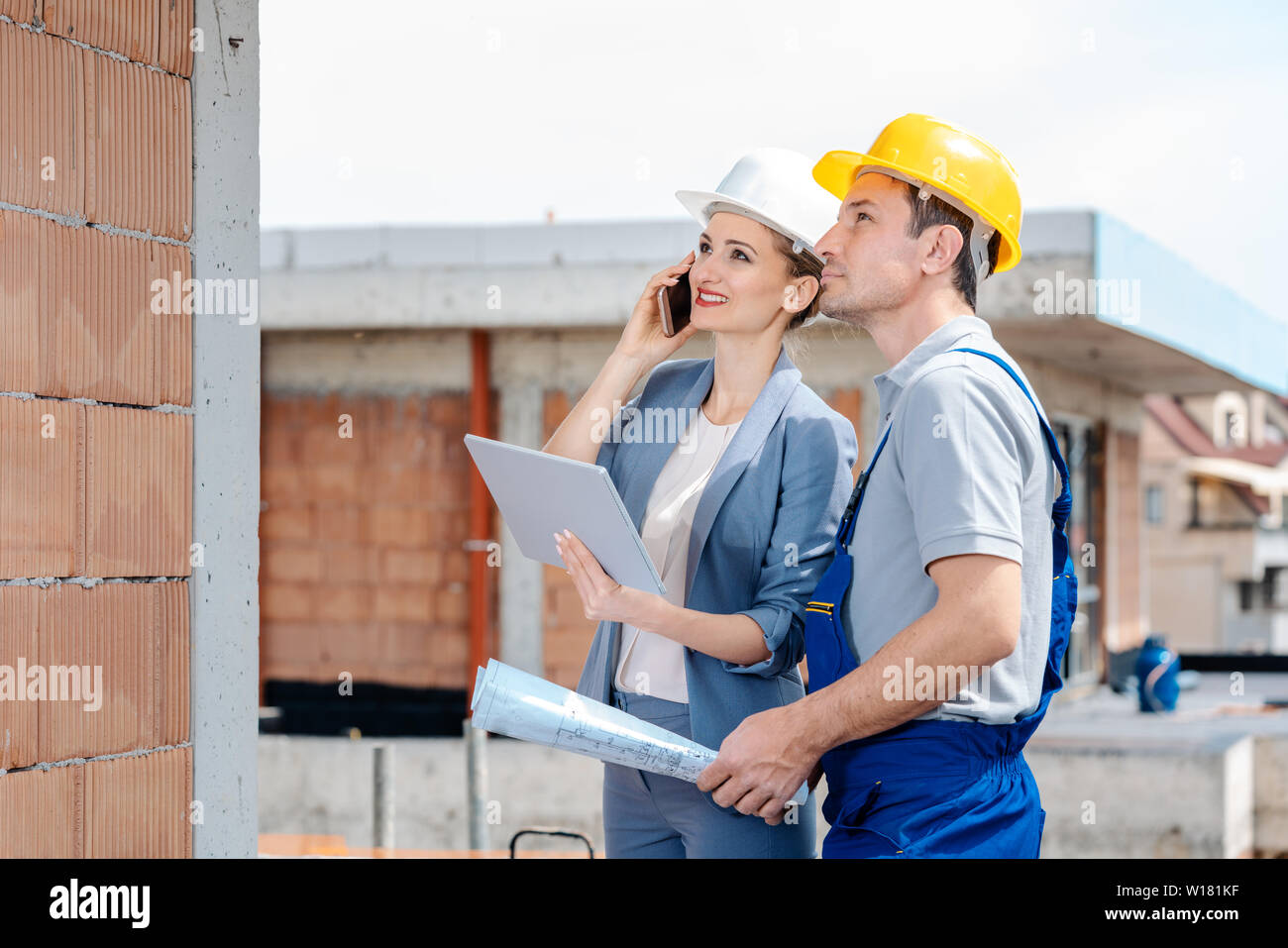 Project developer and construction worker on site using technology like ...