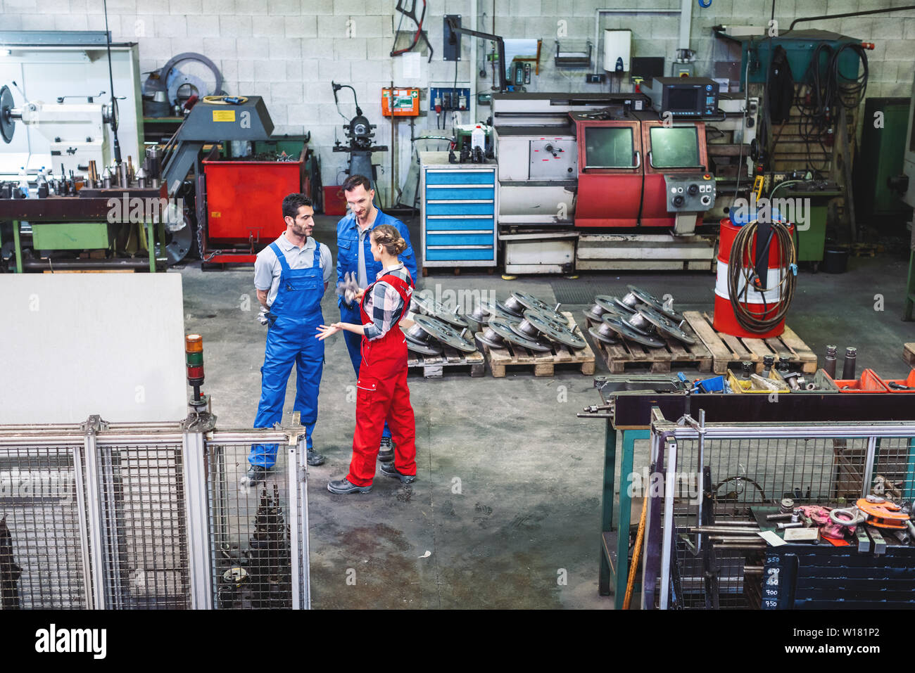 Workers on the factory floor in discussion seen from high viewpoint ...