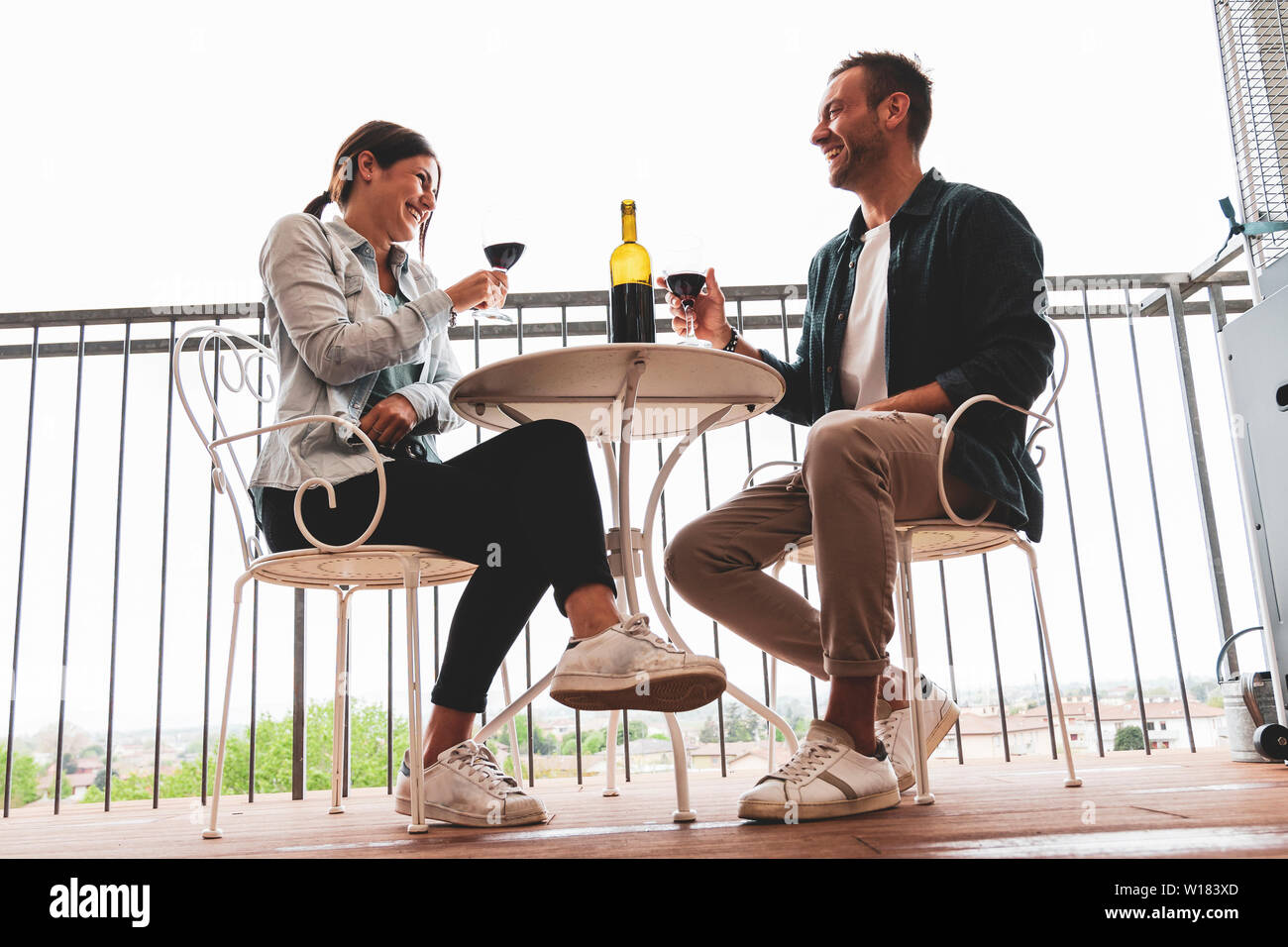 young loving couple celebrating on the terrace of their house drinking ...