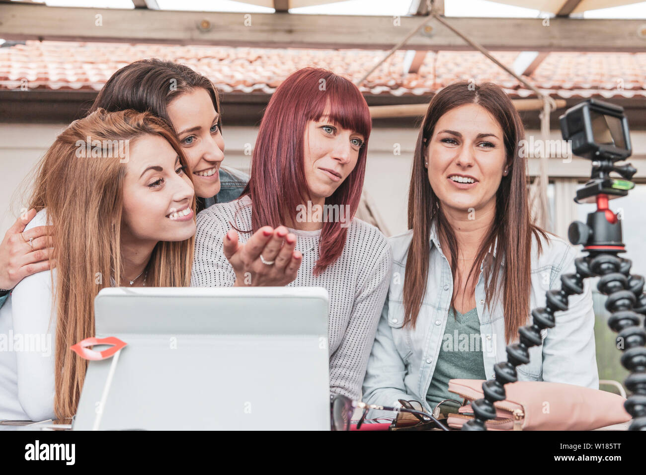 four young vloggers talking on the camera leaning against a small ...