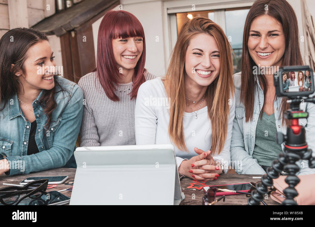 four young vloggers talking on the camera leaning against a small ...