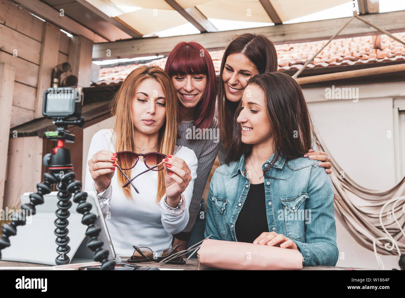 four young vloggers talking on the camera leaning against a small ...