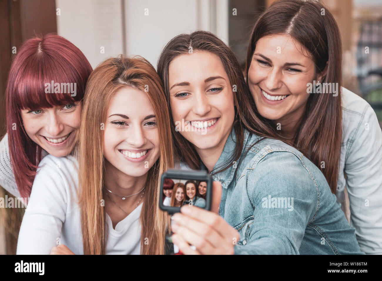 four young vloggers take a selfie with a camera leaning against a small ...
