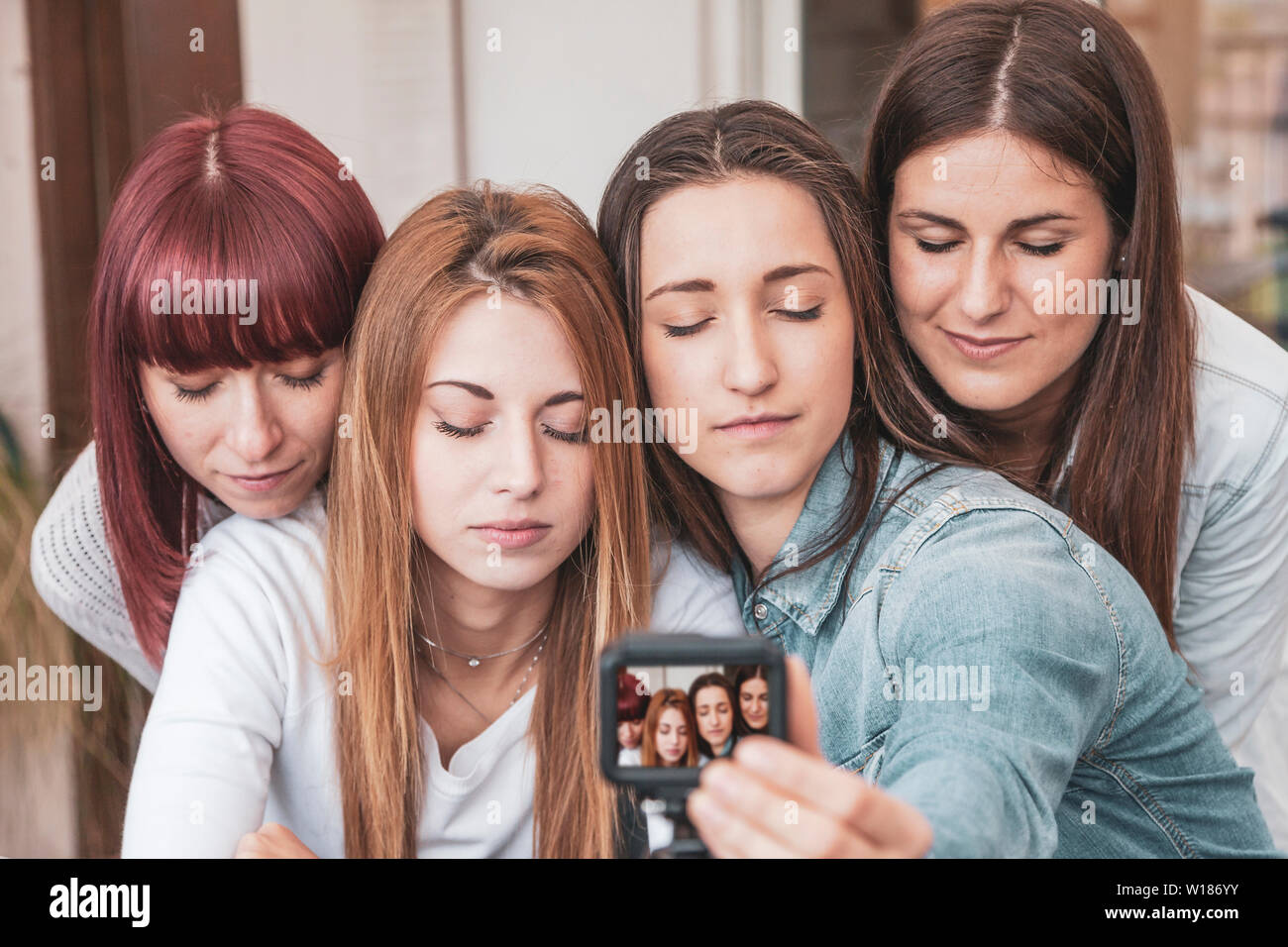 four young vloggers take a selfie with a camera leaning against a small ...