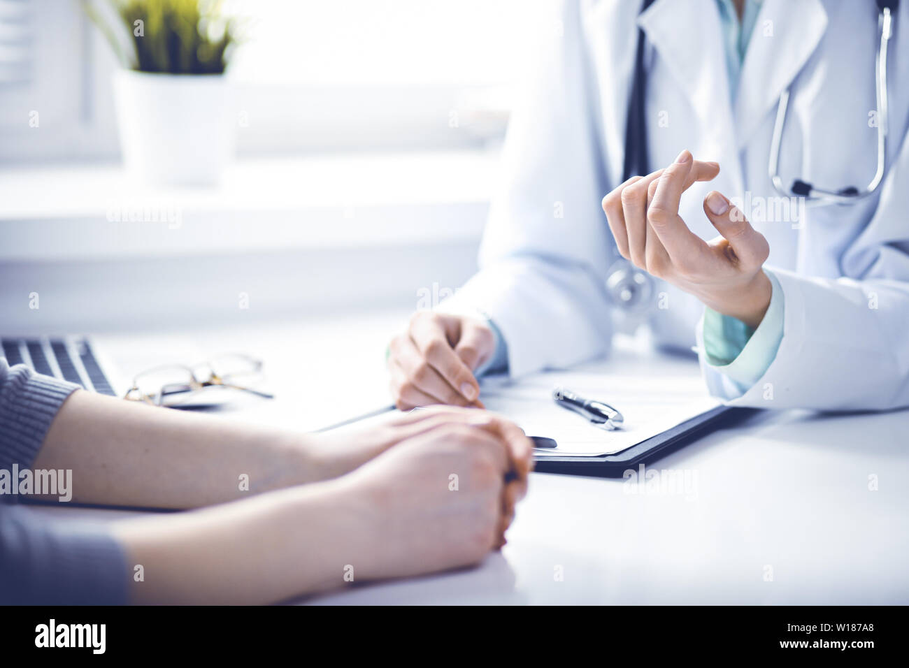 Doctor and female patient sitting at the desk and talking in clinic ...