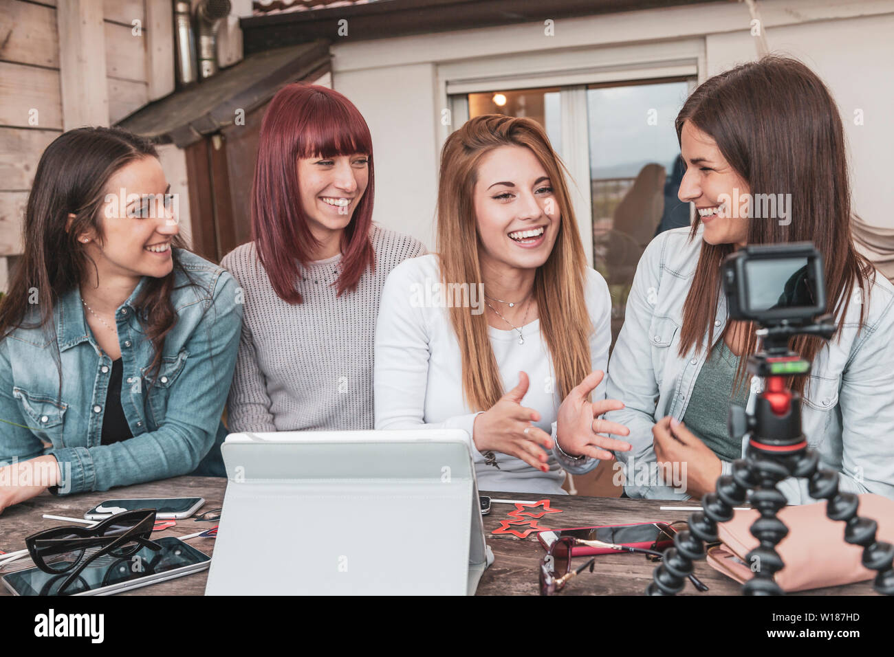 four young vloggers talking on the camera leaning against a small ...