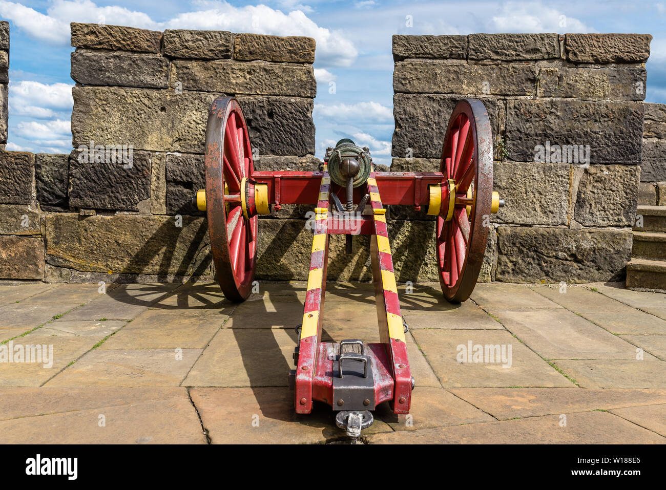 An antique cannon in red-yellow color on the walls of a medieval castle ...