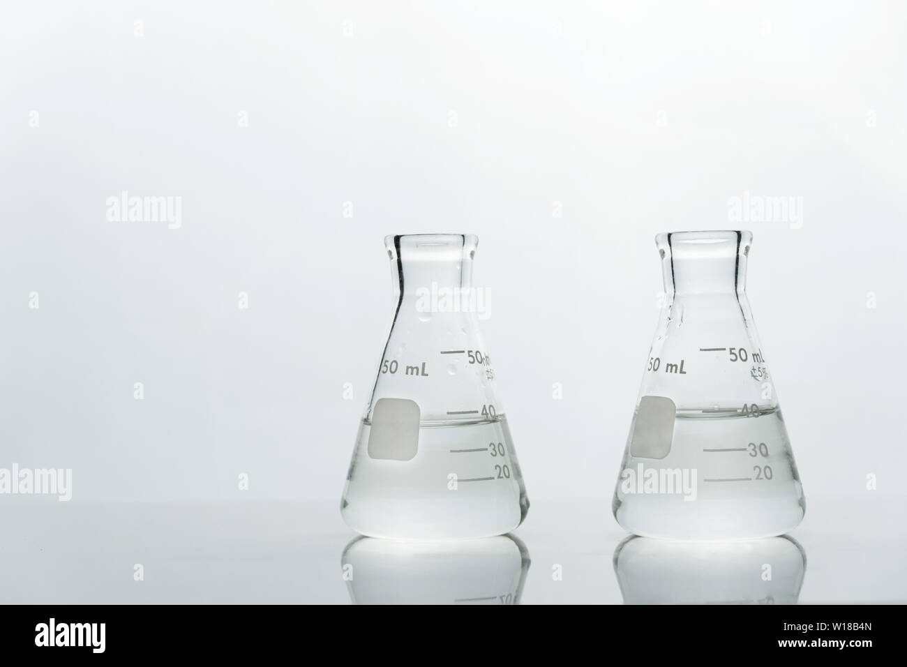 two glass medical science laboratory flask with clear water on white ...