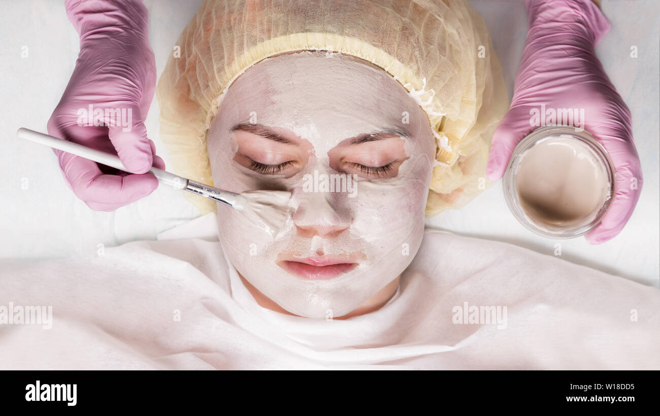 Cosmetologist applying facial mask to problem skin. young woman having ...
