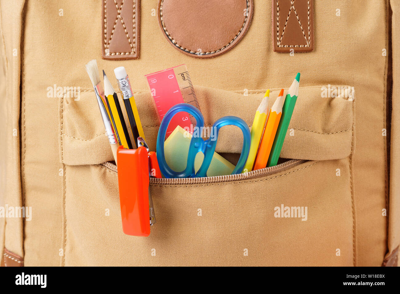 Brown school backpack full of various colorful stationery and supplies ...