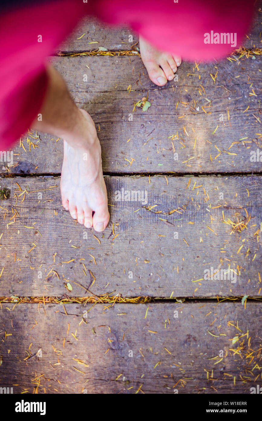 Barefoot feet on a rusty old wooden bridge in the forest, adventure ...