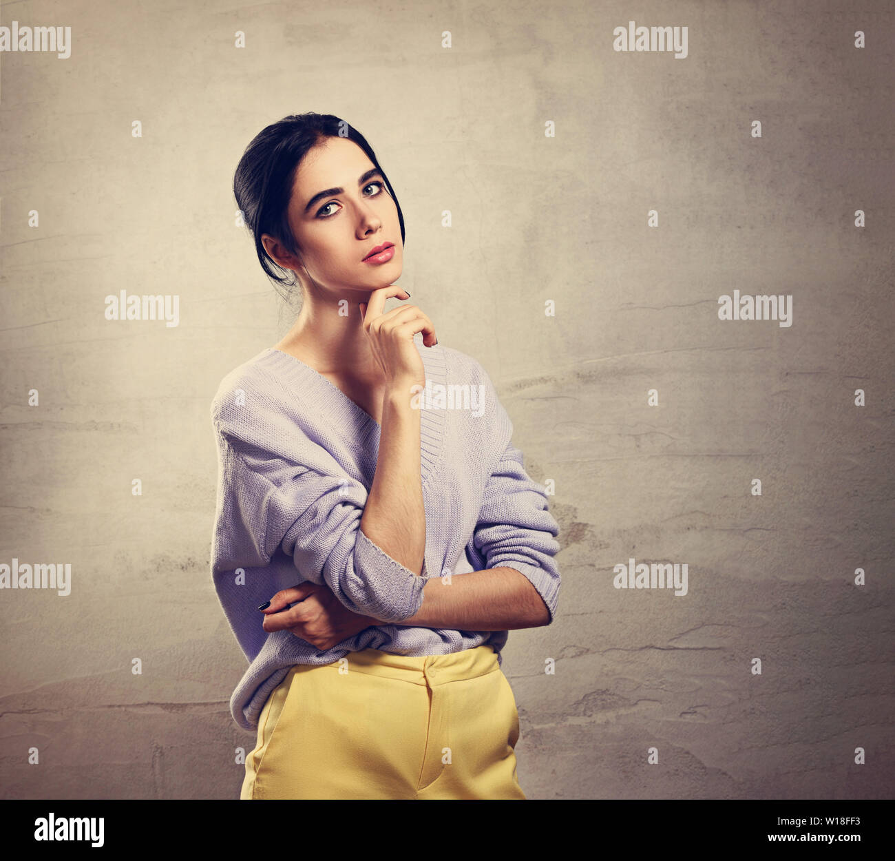 Beautiful thinking sad woman posing with hand under the face in violet ...