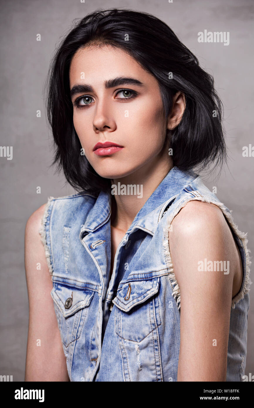 Sad depression young thinking woman posing in blue jeans vest on grey ...