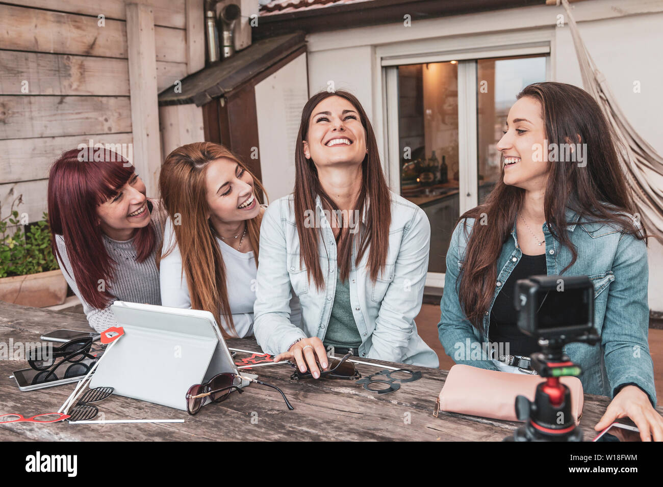four young vloggers talking on the camera leaning against a small ...