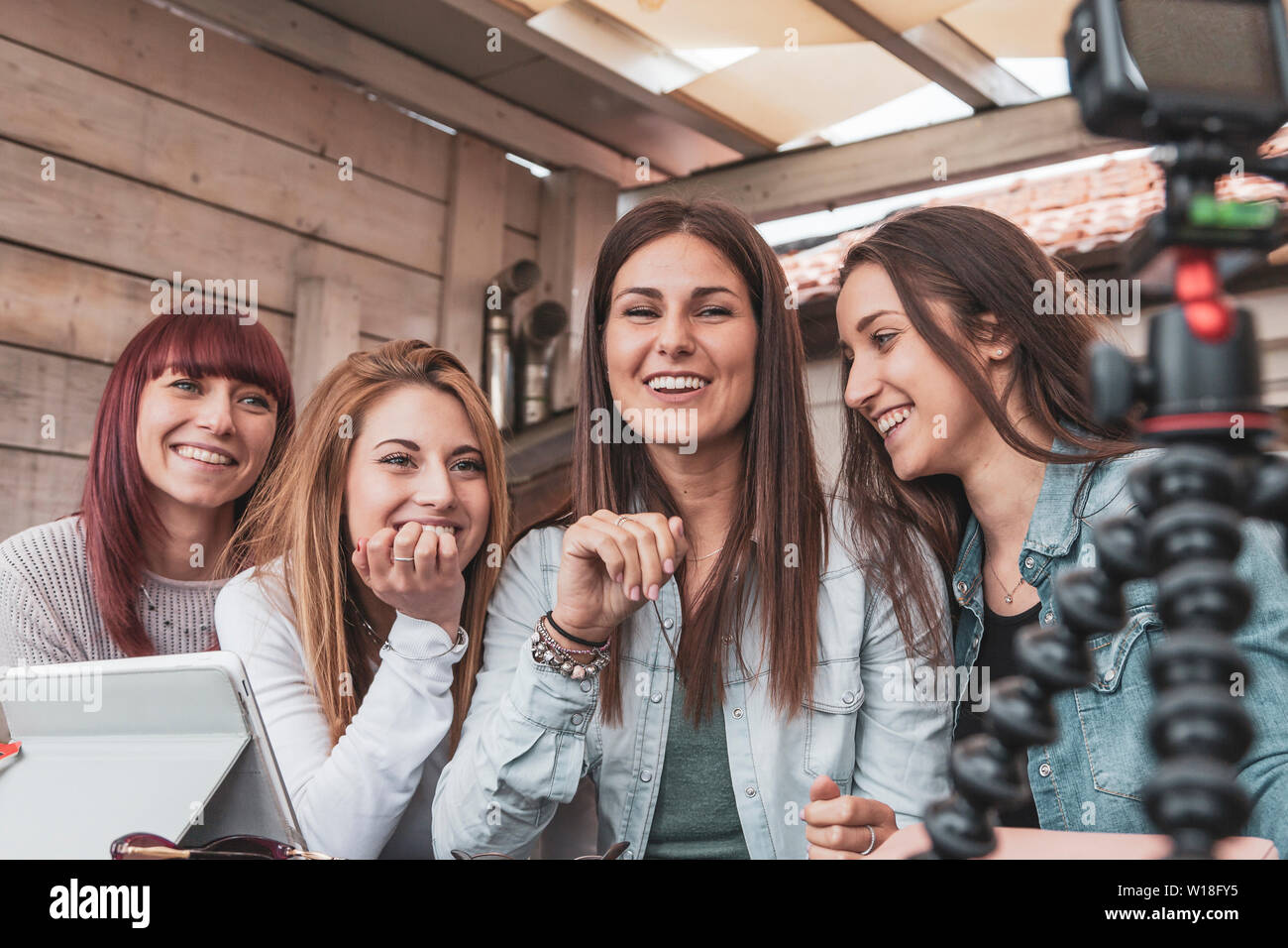 four young vloggers talking on the camera leaning against a small ...