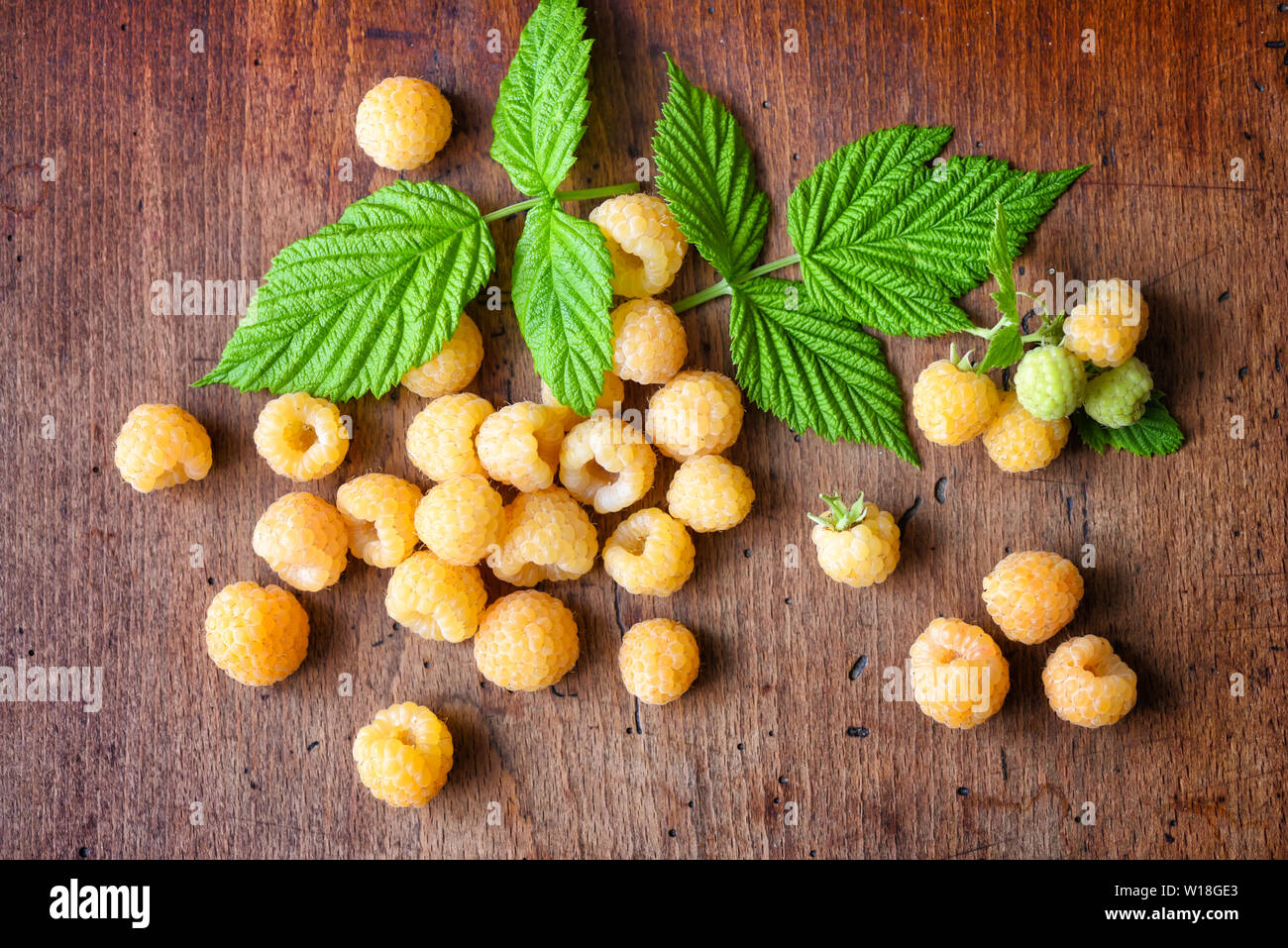 Ripe yellow raspberries with leaves on the old wooden background. Top ...