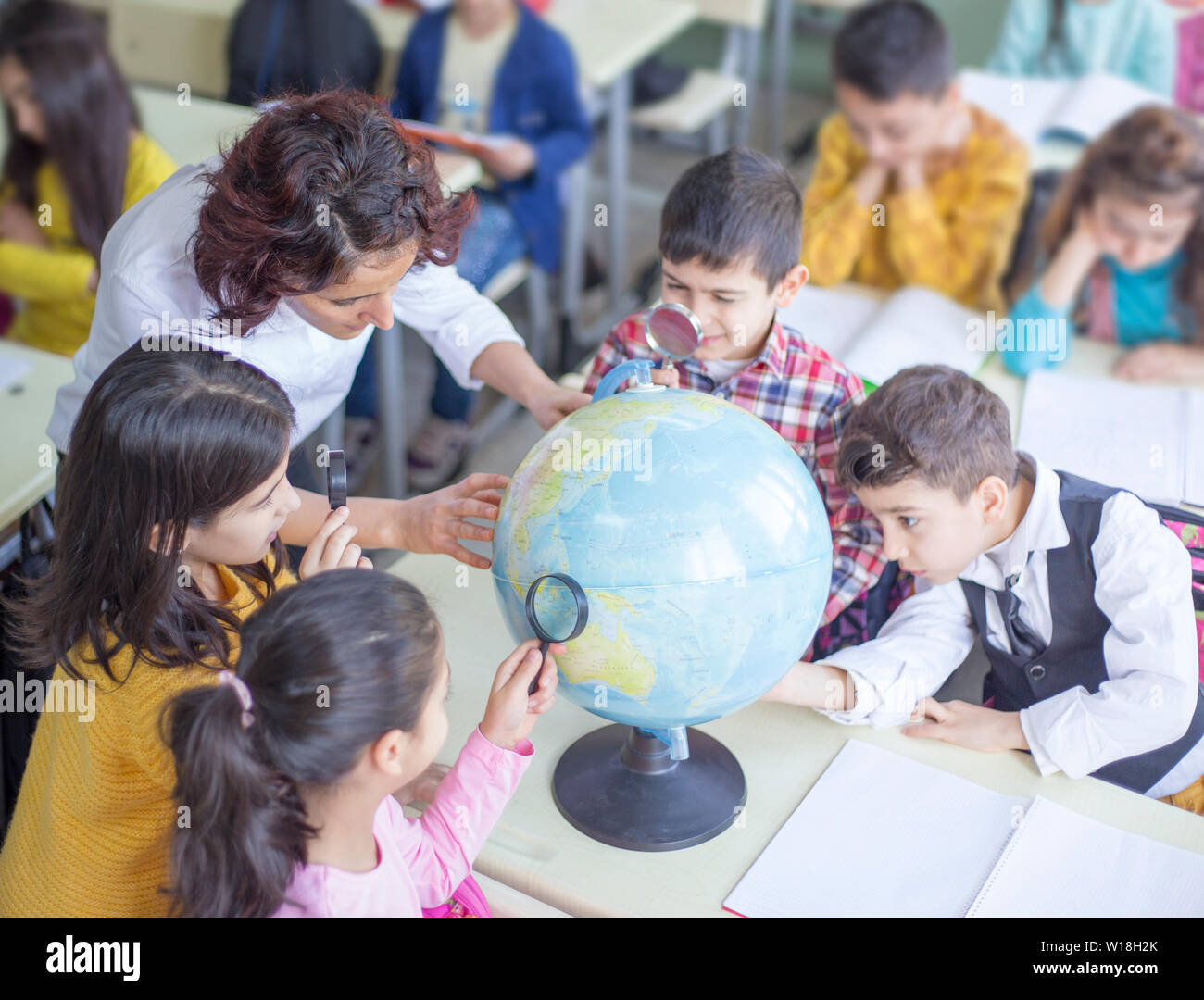 teacher and a group of students examines world map in lecture with ...