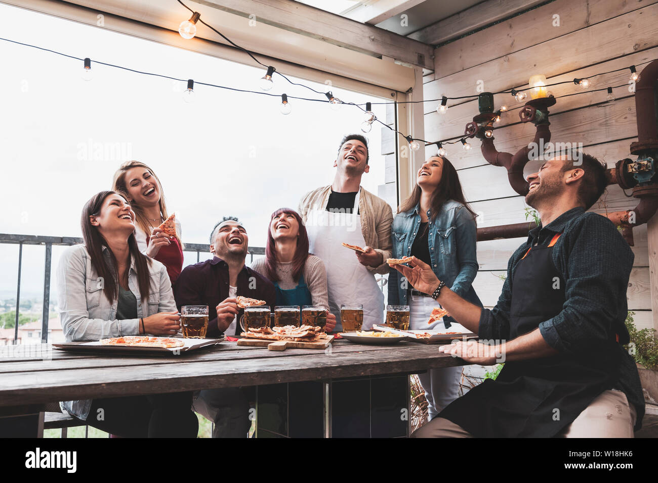 Happy group of friends drinking beer and eating pizza at brewery bar ...