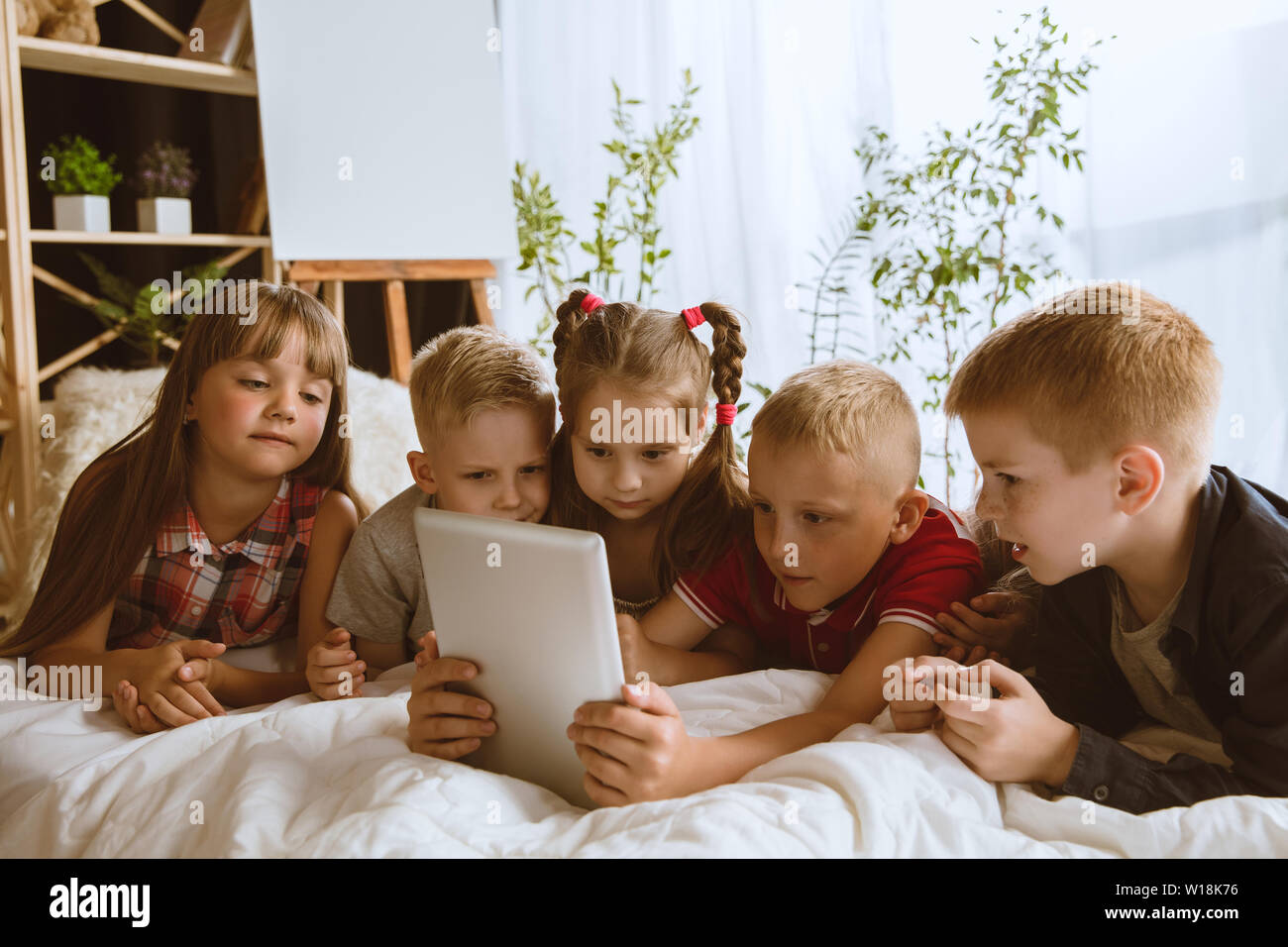 Boys and girls using different gadgets at home. Childs with smart ...