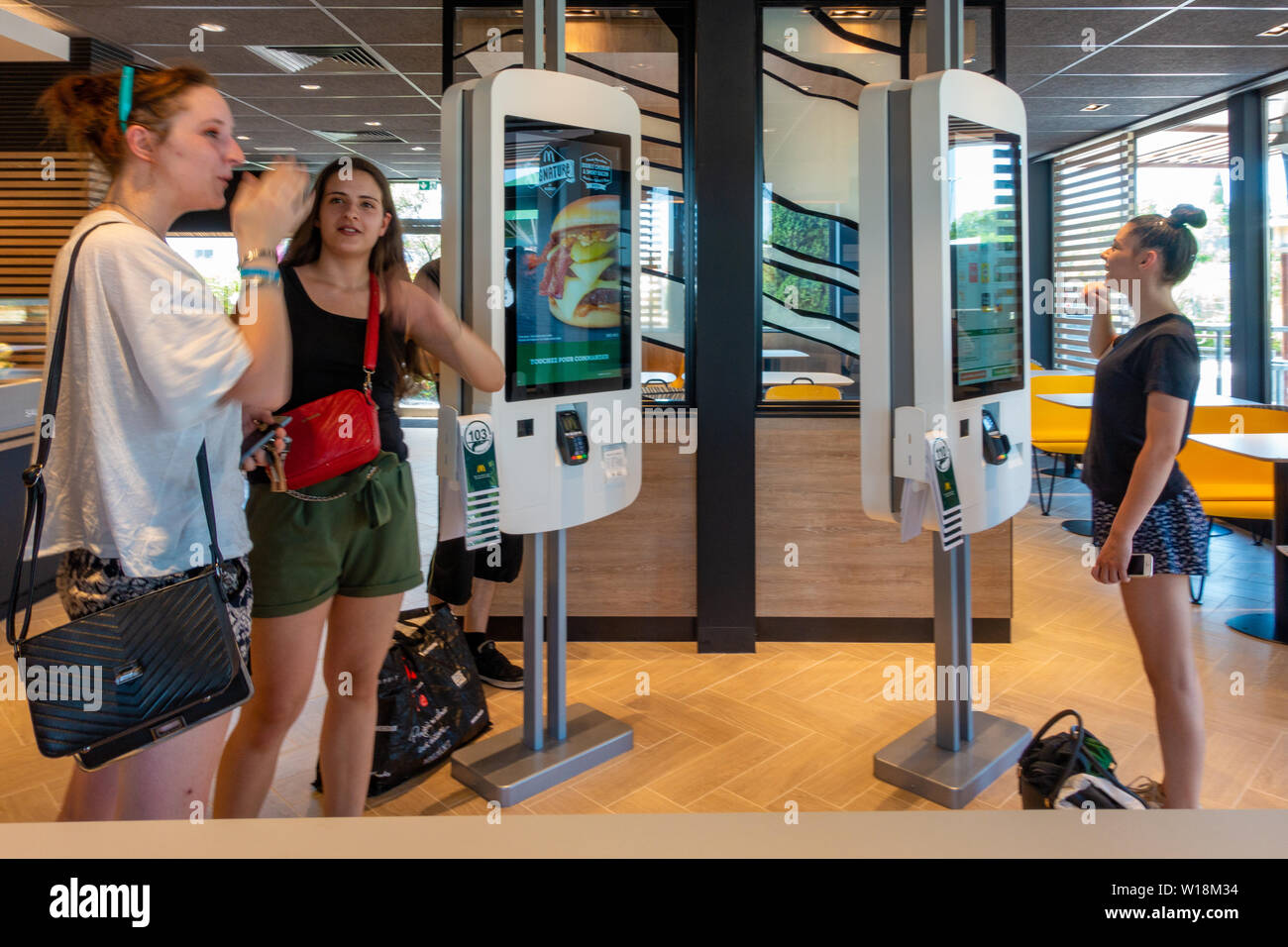 Young people using the automated self-service kiosks at McDonalds Stock ...