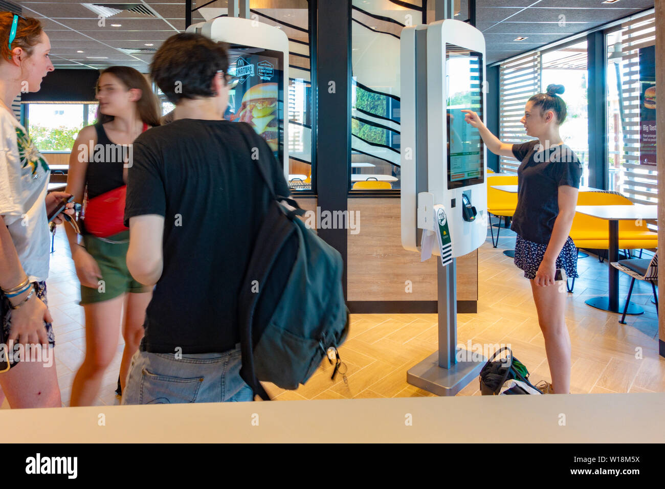 Young people using the automated self-service kiosks at McDonalds Stock ...