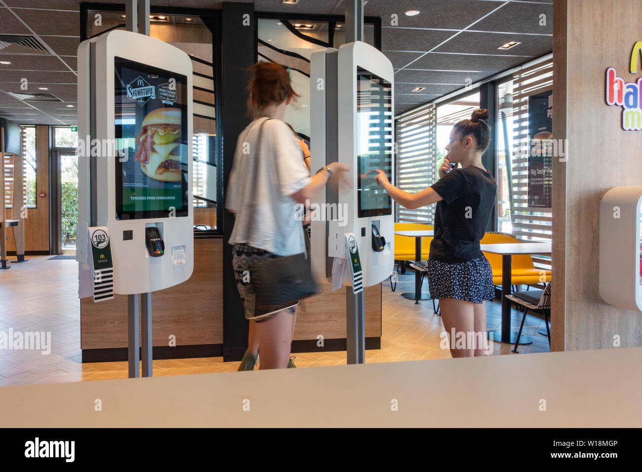 Young people using the automated self-service kiosks at McDonalds Stock ...