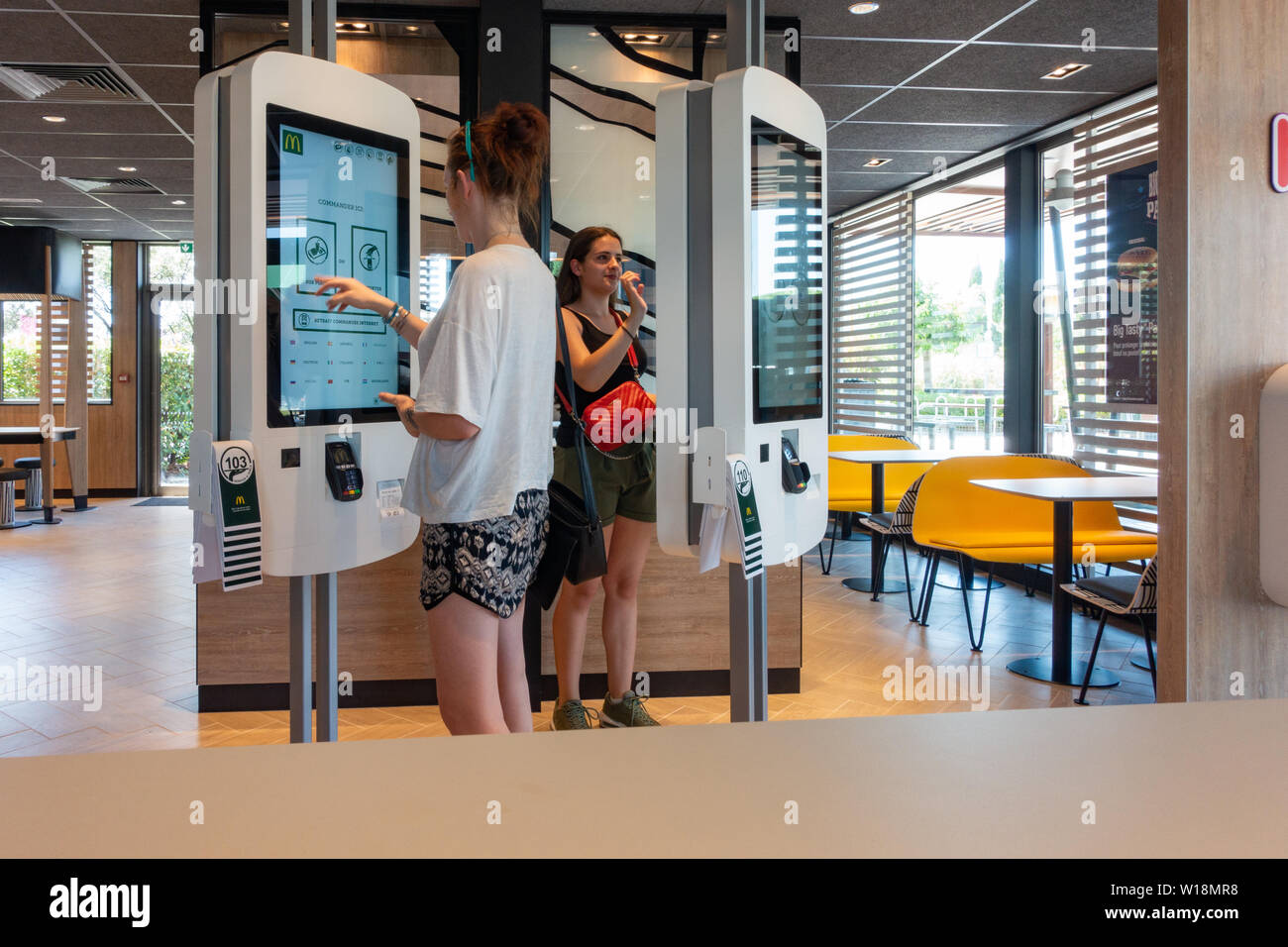 Young people using the automated self-service kiosks at McDonalds Stock ...