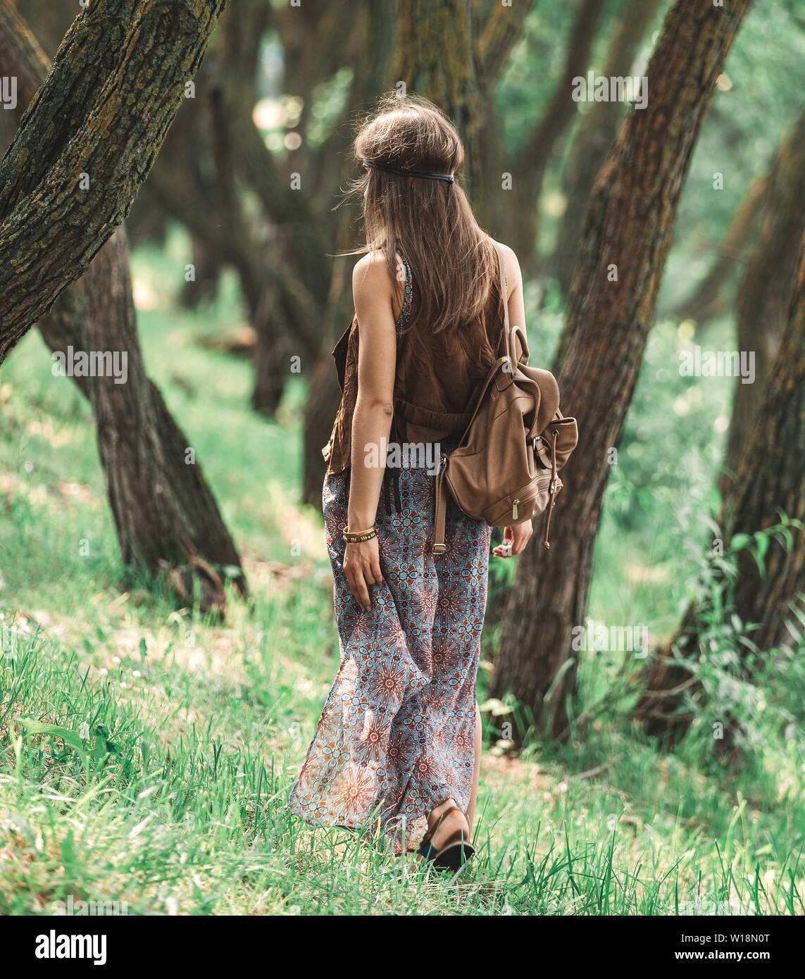 attractive hippie girl walking among the trees in the forest . the ...