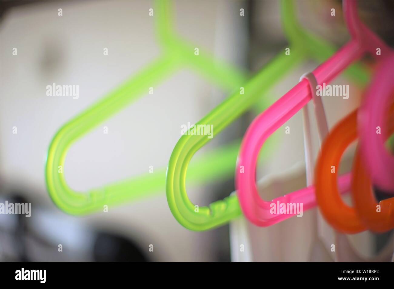 A set of colorful plastic hangers hanging on the rack Stock Photo - Alamy