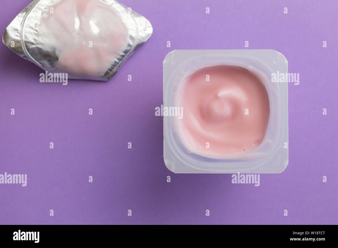 Healthy strawberry fruit flavored pink yoghurt in small plastic cup ...