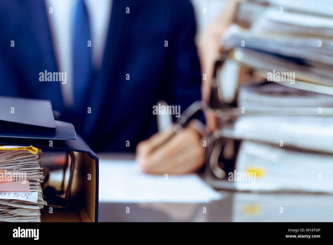 Binders with papers waiting to be processed with businessman or ...
