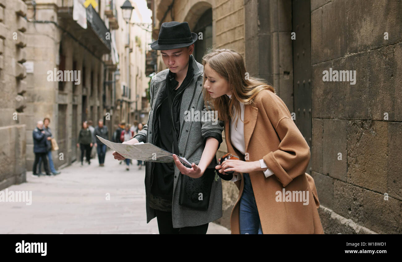 Two stylish friend standing at the street and look for something using ...
