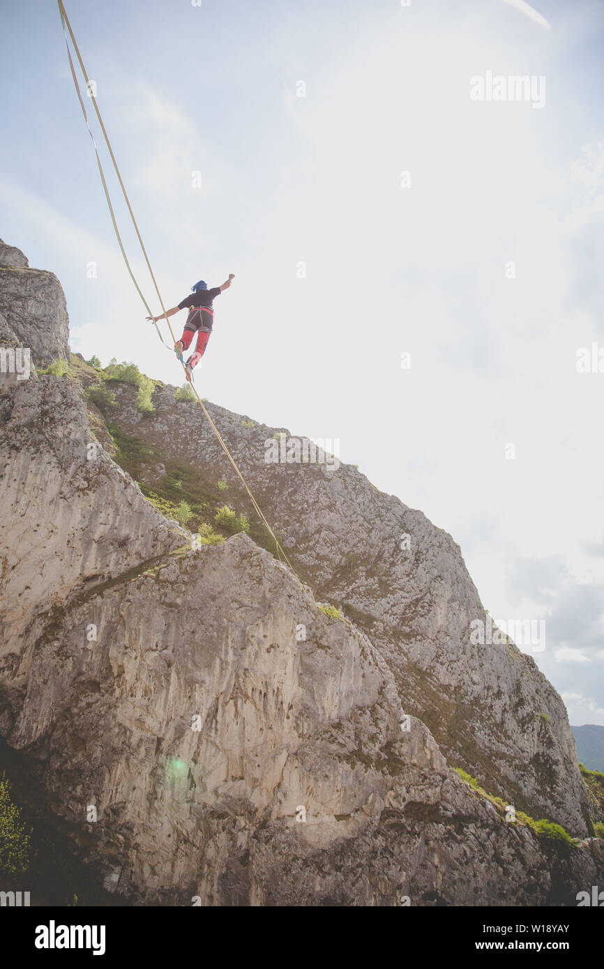 Young man balancing on a slackline high above cliffs. Highline in ...
