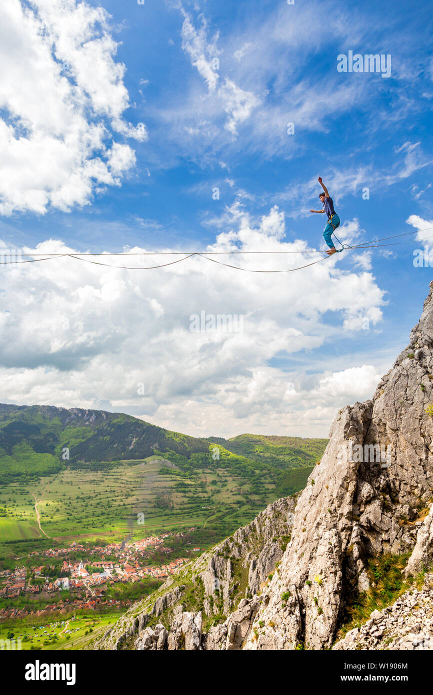 Young man balancing on a slackline high above cliffs. Highline in ...