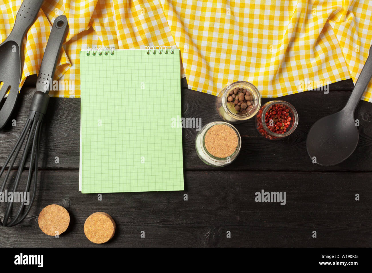 Blank sheet of opened notepad and kitchen utensils on table with ...