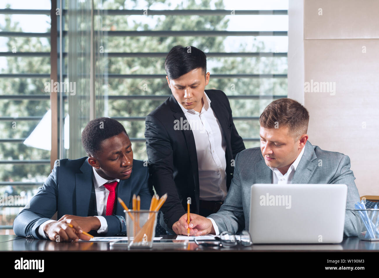 Business people meeting around a boardroom table discussing strategy ...