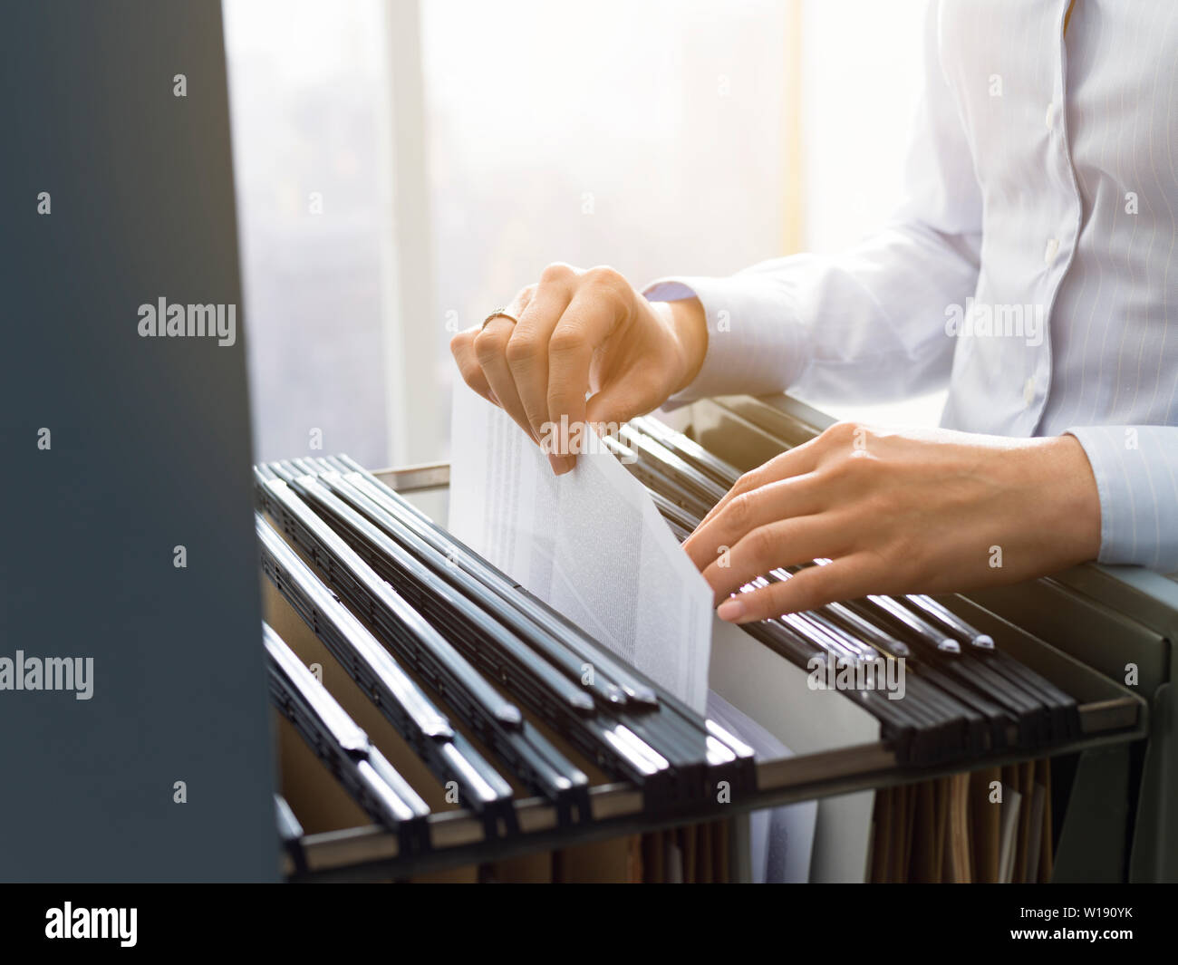 Professional female office clerk searching files and paperwork in the ...