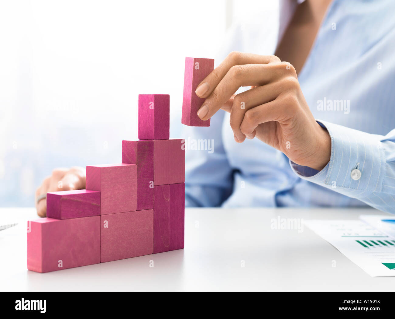 Businesswoman building a growing financial chart with wooden pieces ...