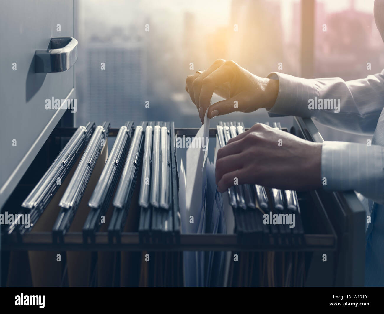 Professional female office clerk searching files and paperwork in the ...