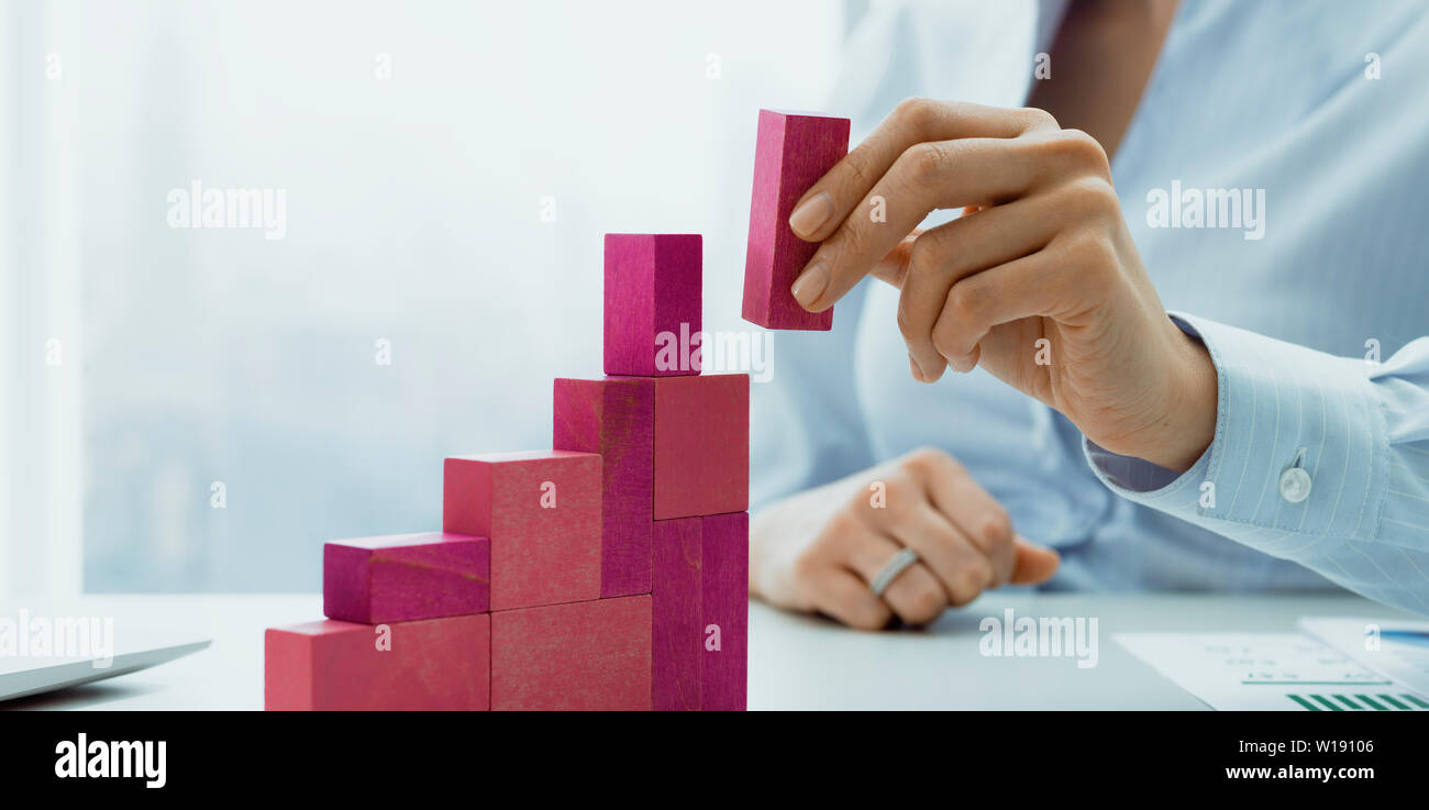 Businesswoman building a growing financial chart with wooden pieces ...
